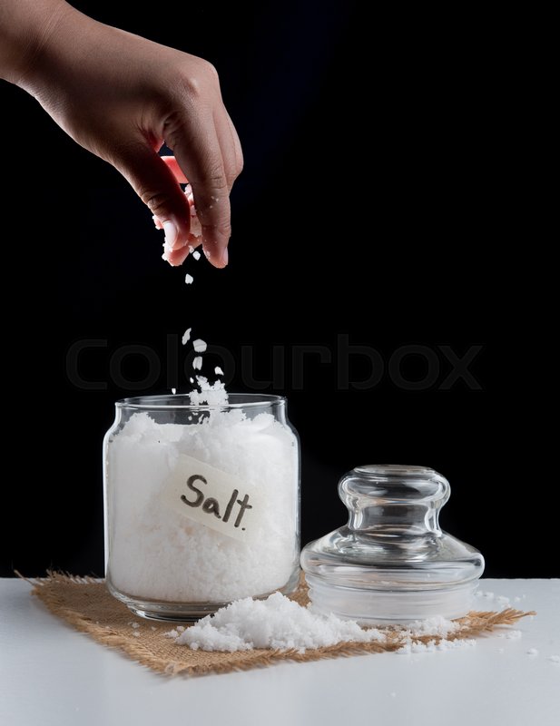 Hand sprinkling salt into glass jar ... | Stock image | Colourbox