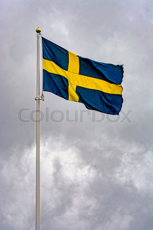 Sveriges flag, med en grå himmel som ... | Stock foto | Colourbox