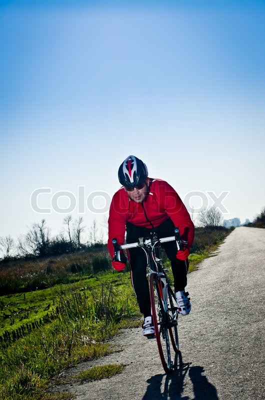 Man on road bike riding down open ... | Stock image | Colourbox