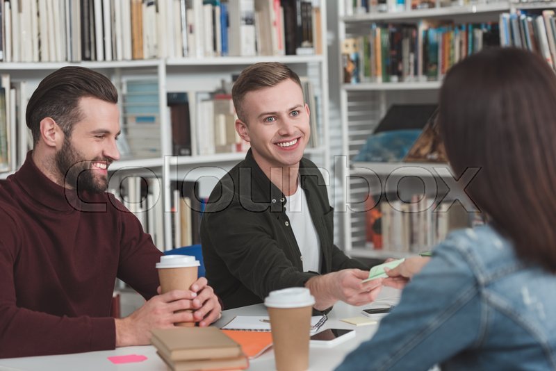 Smiling students in library with ... | Stock image | Colourbox