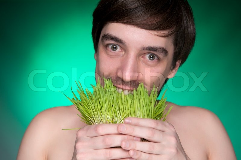 Young man eating a bunch of fresh green ... | Stock image | Colourbox
