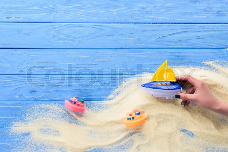 Woman playing with toy boat on blue ... | Stock image | Colourbox
