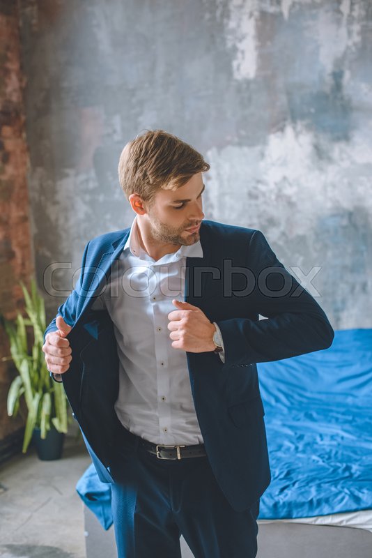 Serious businessman putting on jacket ... | Stock image | Colourbox