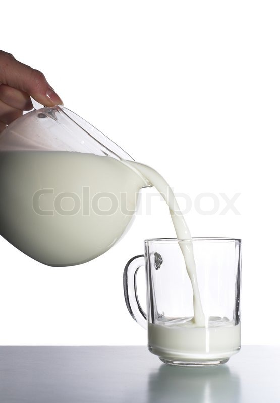 Milk pouring from the pot into glass ... | Stock image | Colourbox