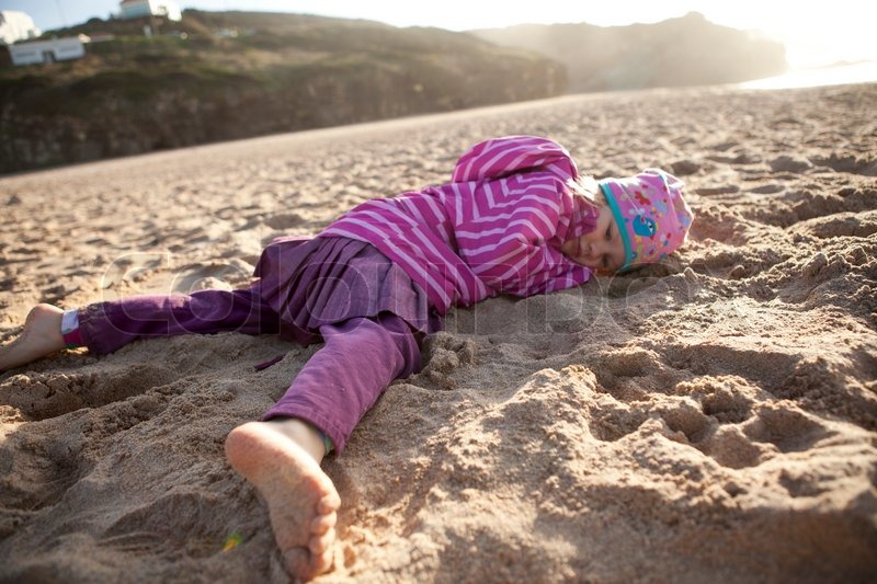 Cute little girl lying in sand on the ... | Stock image | Colourbox