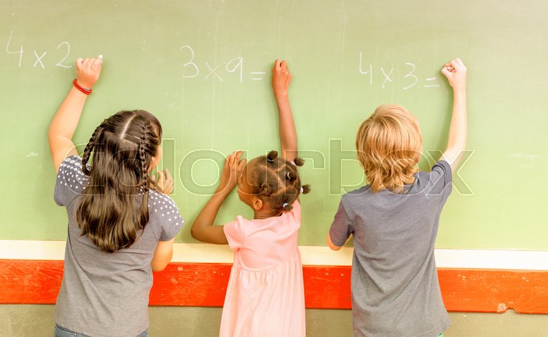 Mixed race school children writing on ... | Stock image | Colourbox