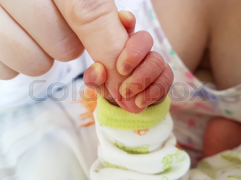 Baby's hand wrapped around finger | Stock image | Colourbox