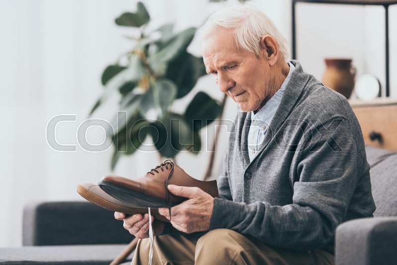Senior man holding shoes in hands while ... | Stock image | Colourbox