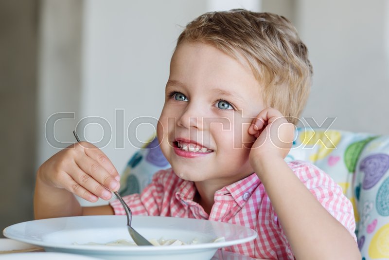 Happy little boy eating soup in the ... | Stock image | Colourbox