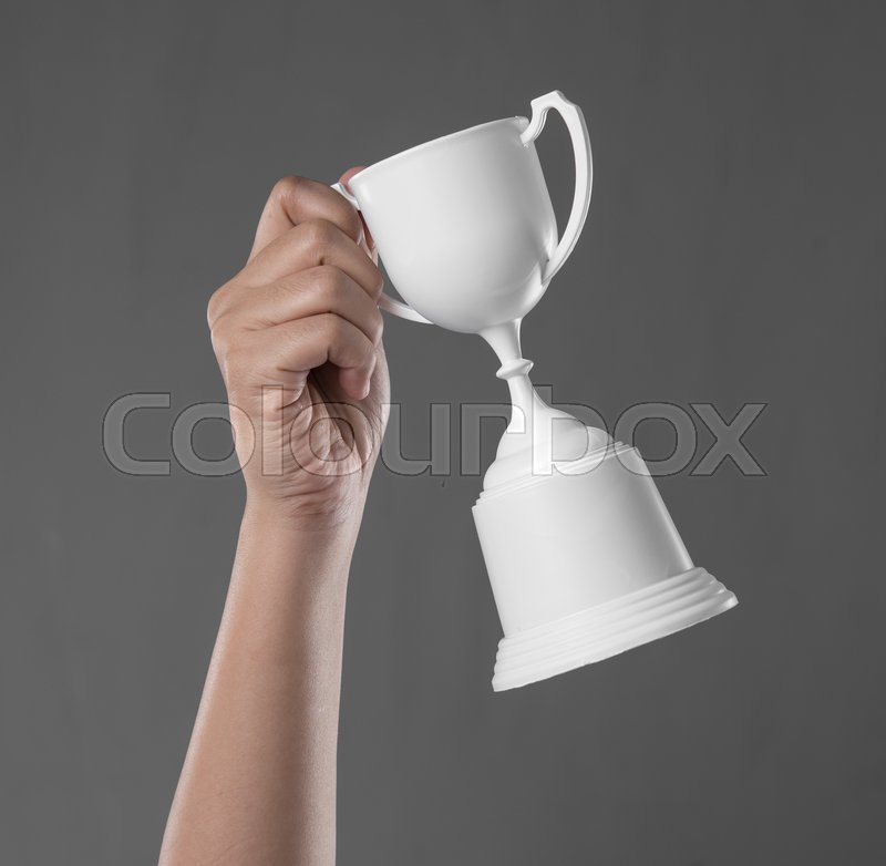 Hand holding up a white trophy cup as a ... | Stock image | Colourbox