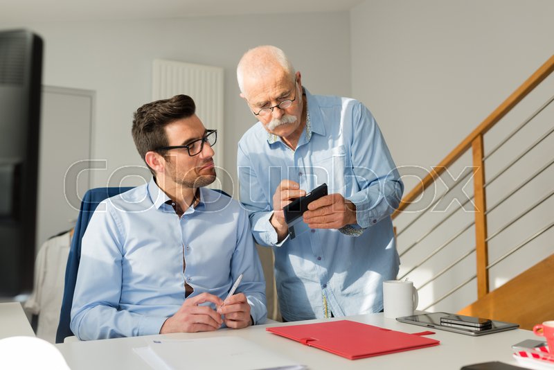 Older male colleague showing something ... | Stock image | Colourbox