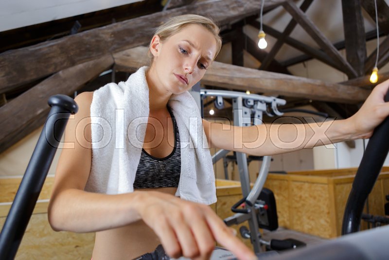 Woman setting up exercise machine | Stock image | Colourbox