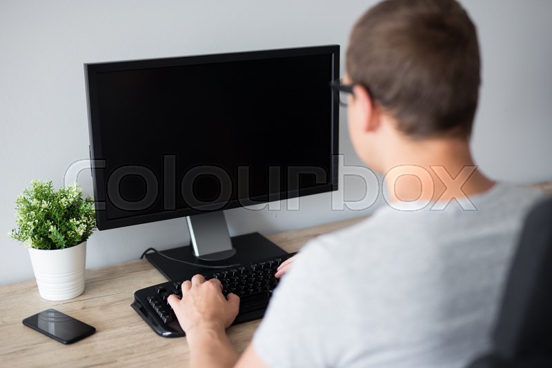 Back view of young man using computer ... | Stock image | Colourbox