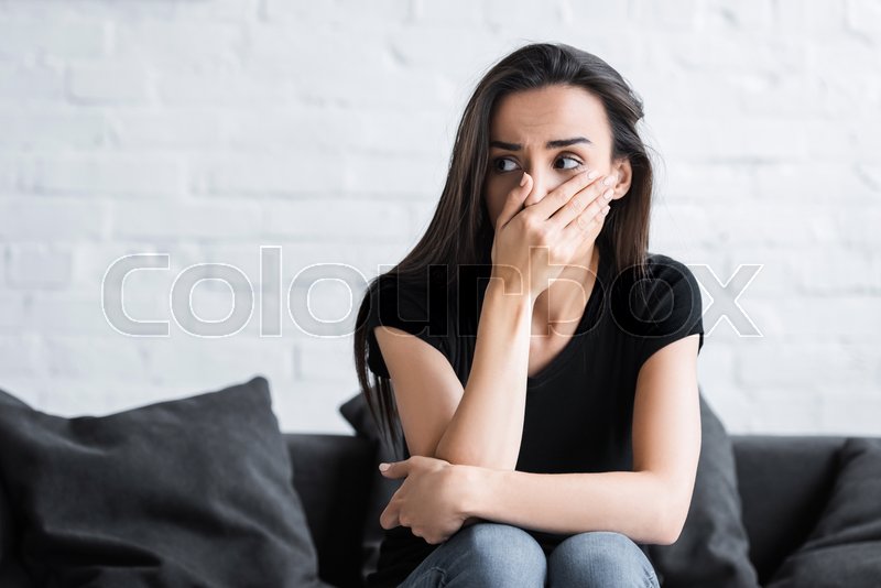 Scared young woman holding hand on face ... | Stock image | Colourbox