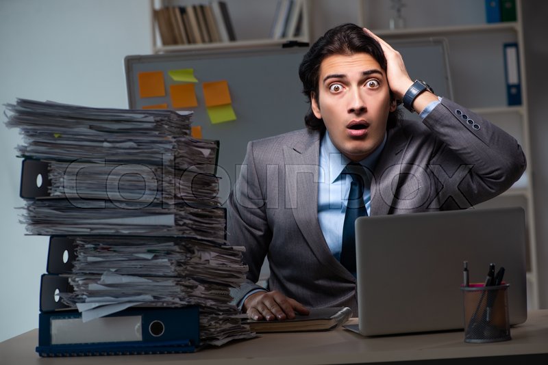 The young male employee working late at ... | Stock image | Colourbox