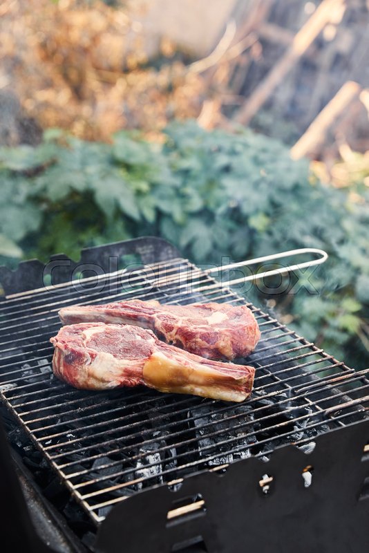Raw meat grilling on barbecue grid and ... | Stock image | Colourbox