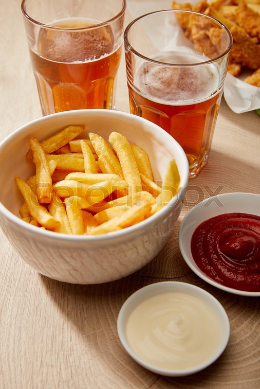 Glasses of beer, french fries in bowl, ... | Stock image | Colourbox