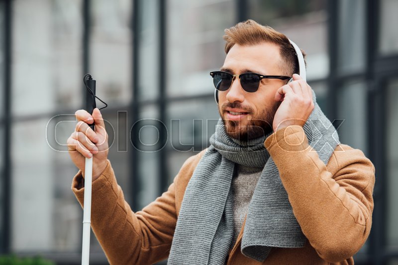 Smiling blind man using headphones and ... | Stock image | Colourbox