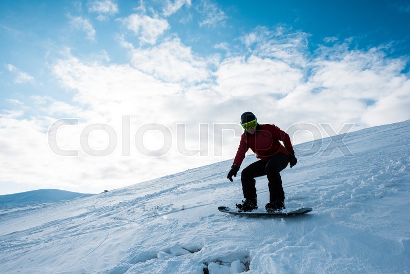 Athletic snowboarder riding on slope ... | Stock image | Colourbox