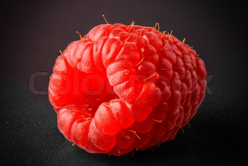 One fresh raspberry closeup on a black ... | Stock image | Colourbox