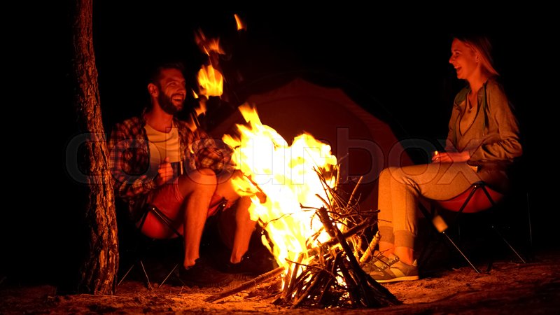 Two campers warming up near campfire, ... | Stock image | Colourbox