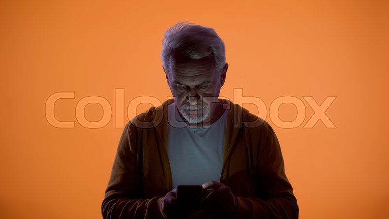 Upset old man typing message on ... | Stock image | Colourbox