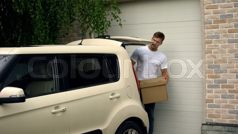 Casual male putting cardboard box in ... | Stock image | Colourbox