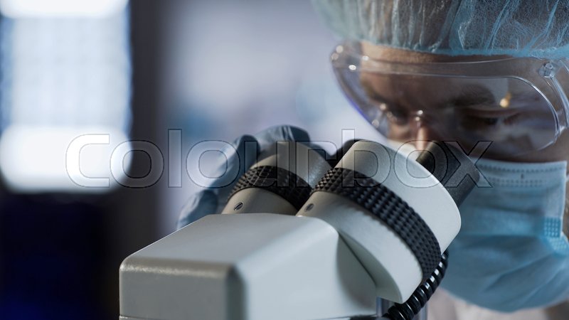 Male scientist in face mask examining ... | Stock image | Colourbox