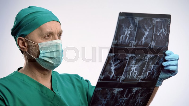 Neurosurgeon in face mask observing MRI ... | Stock image | Colourbox
