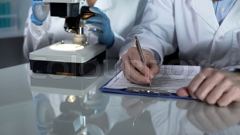 Lab worker filling paper forms, his ... | Stock image | Colourbox