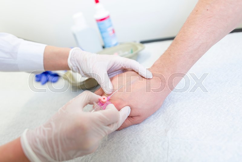 Doctor injects an infusion needle into ... | Stock image | Colourbox