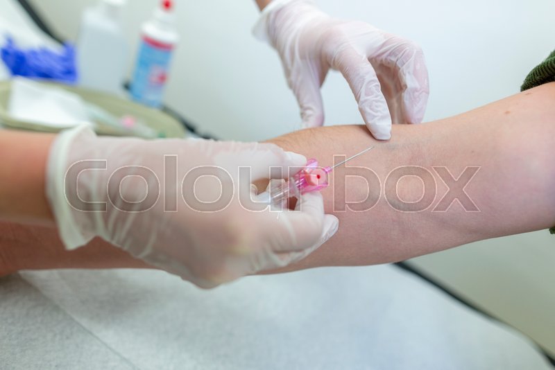 Doctor injects an infusion needle into ... | Stock image | Colourbox