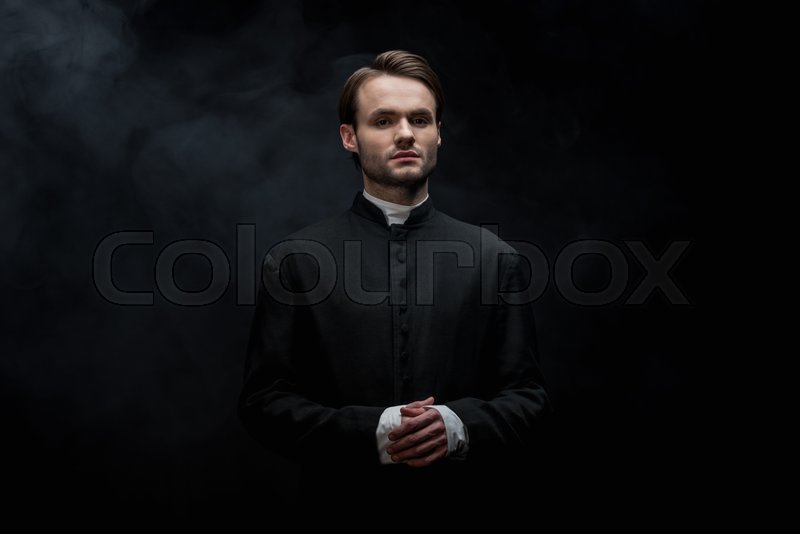 Young serious catholic priest standing ... | Stock image | Colourbox