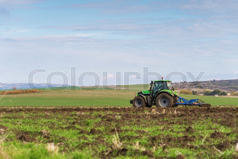 Farmer in tractor preparing land with ... | Stock image | Colourbox