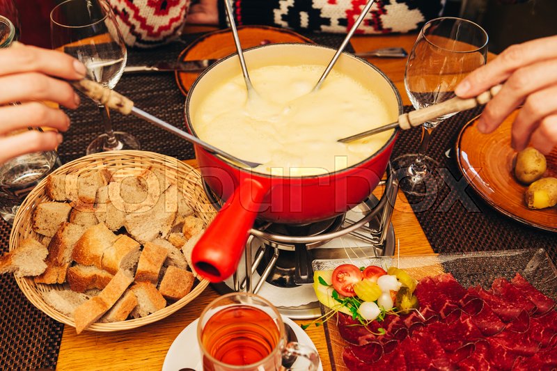 Friends eating cheese fondue in a cozy ... | Stock image | Colourbox