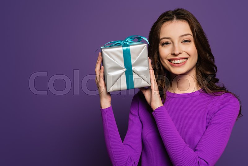 Cheerful girl showing gift box while ... | Stock image | Colourbox