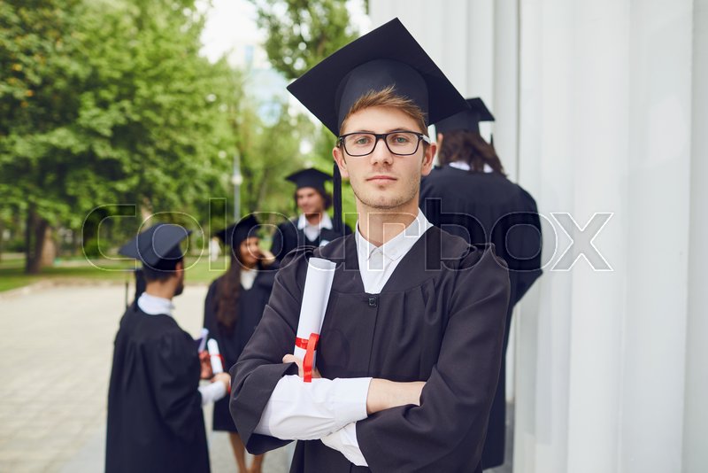 A young man graduate with a scroll in ... | Stock image | Colourbox