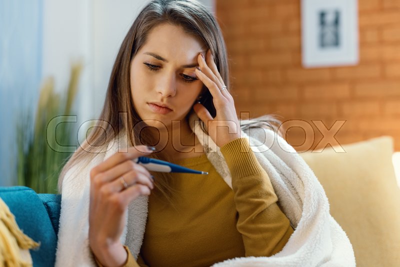 Sick woman sitting on the sofa at home ... - Stock Image - Everypixel
