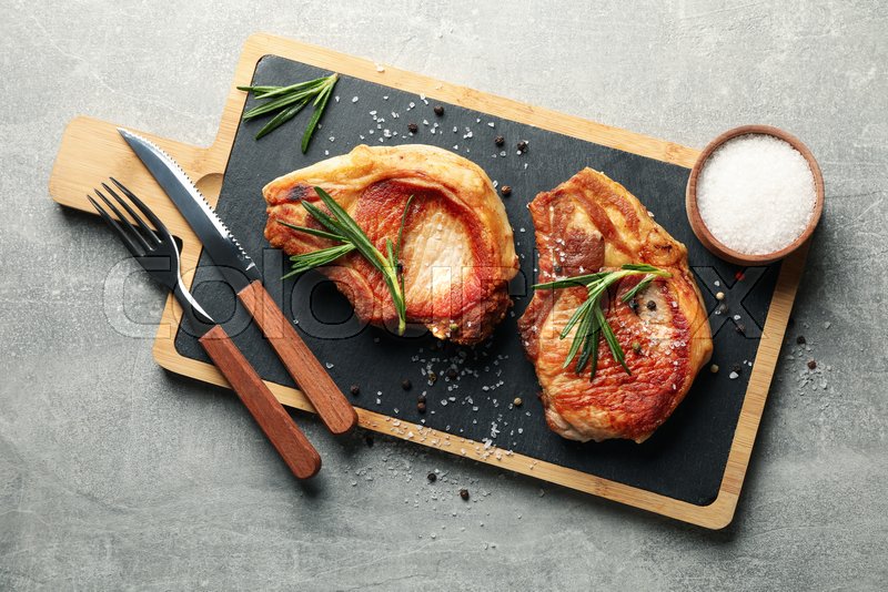 Board with steaks and cutlery on gray ... | Stock image | Colourbox