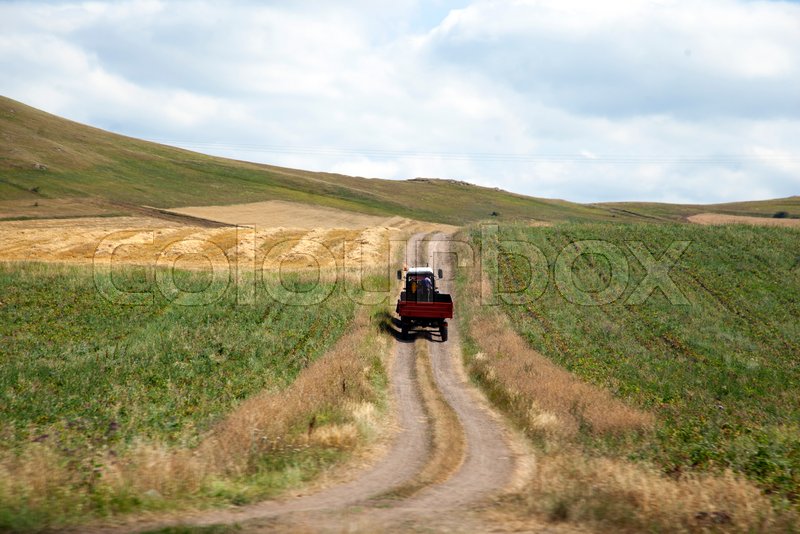 A tractor driving across farmlands. ... | Stock image | Colourbox