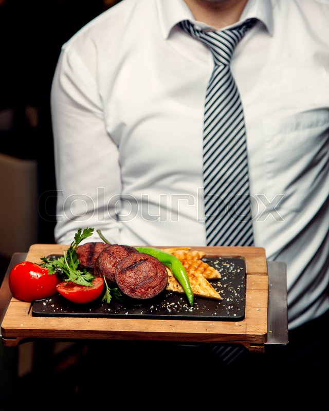 Waiter holding a platter of grilled ... | Stock image | Colourbox