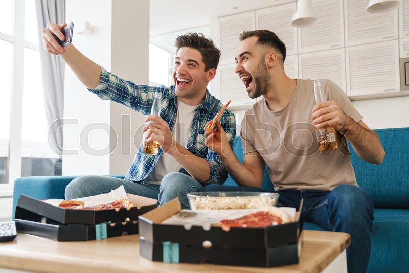 Photo of young excited two guys eating ... | Stock image | Colourbox