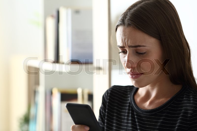 Sad woman checking smart phone content ... | Stock image | Colourbox