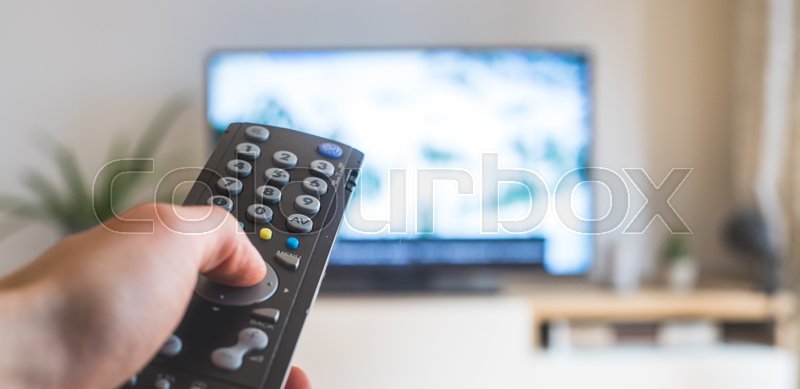 Holding a TV remote control in the ... | Stock image | Colourbox