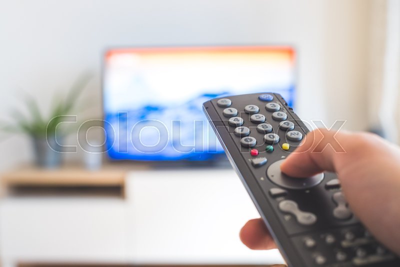 Holding a TV remote control in the ... | Stock image | Colourbox