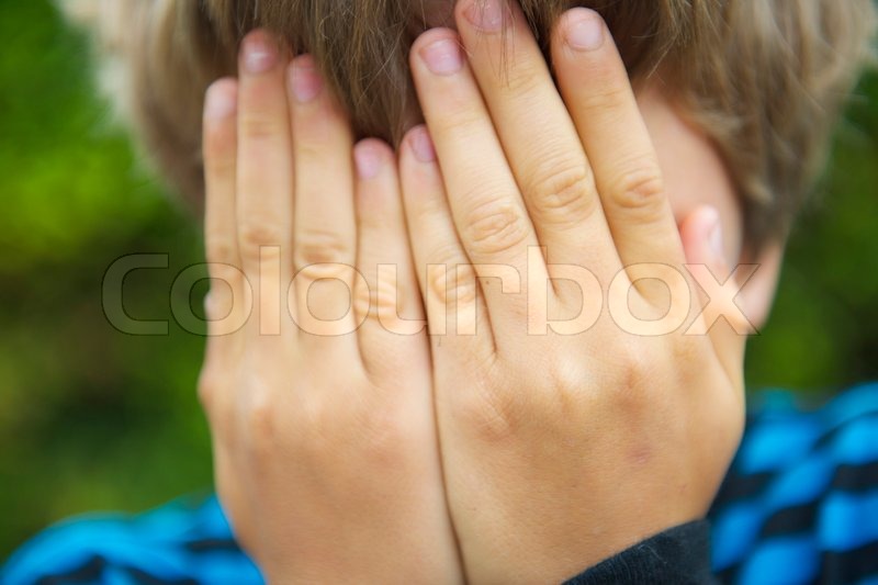 Scared or shy boy with hands covering ... | Stock image | Colourbox