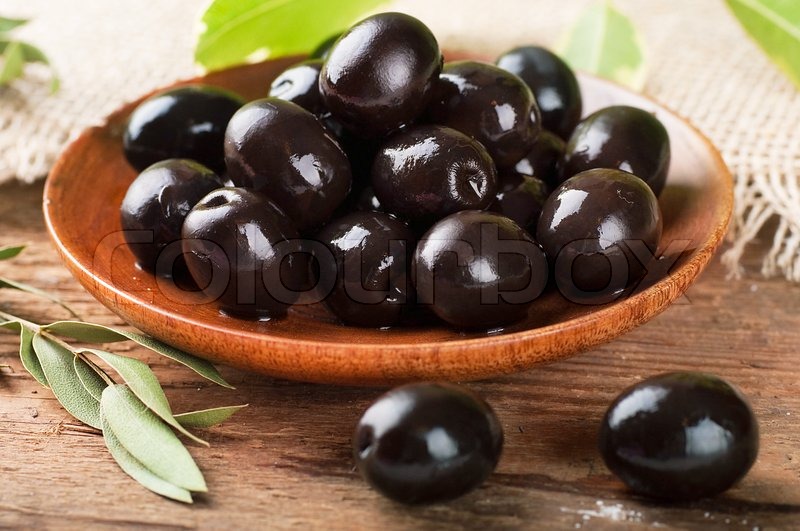 Sorte oliven i en træplade og en ru ... | Stock foto | Colourbox