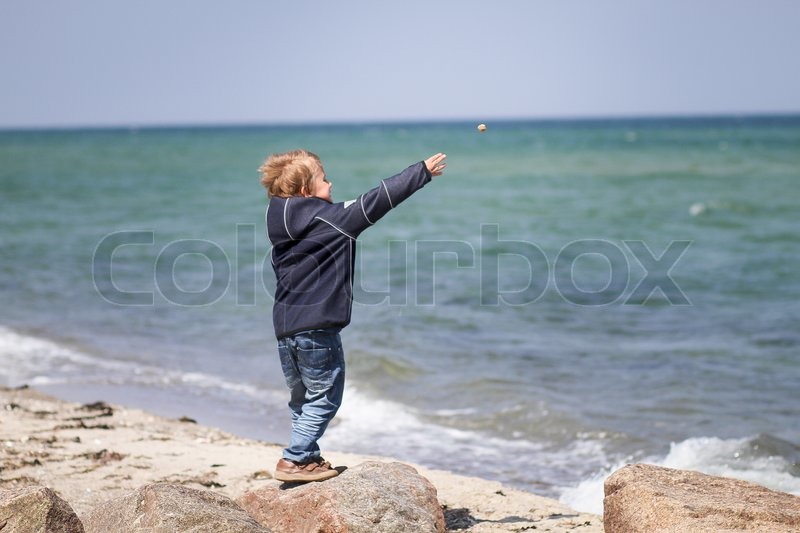 Young boy throwing stones in the water ... | Stock image | Colourbox