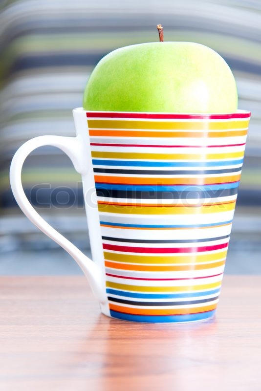 Green apple in a cup on wooden table | Stock image | Colourbox