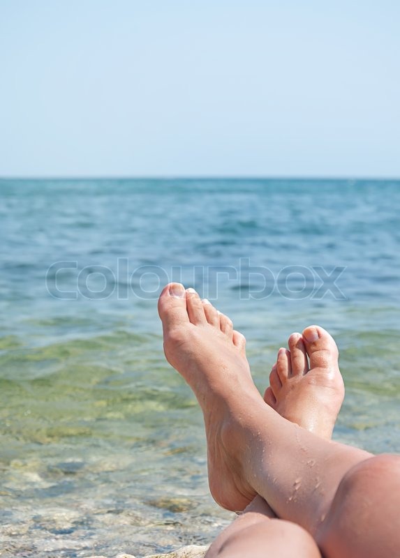 Two female legs on beach over sea waves ... | Stock image | Colourbox